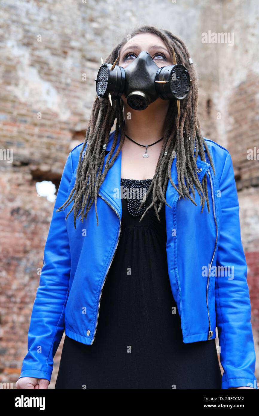 Woman wearing gas mask with spikes in blue jacket and black dress ...