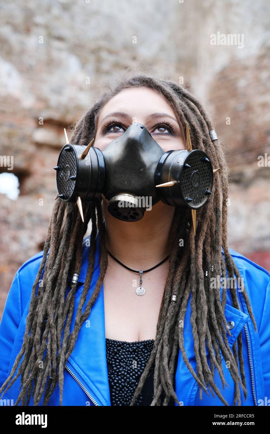Woman wearing gas mask with spikes in blue jacket and black dress ...