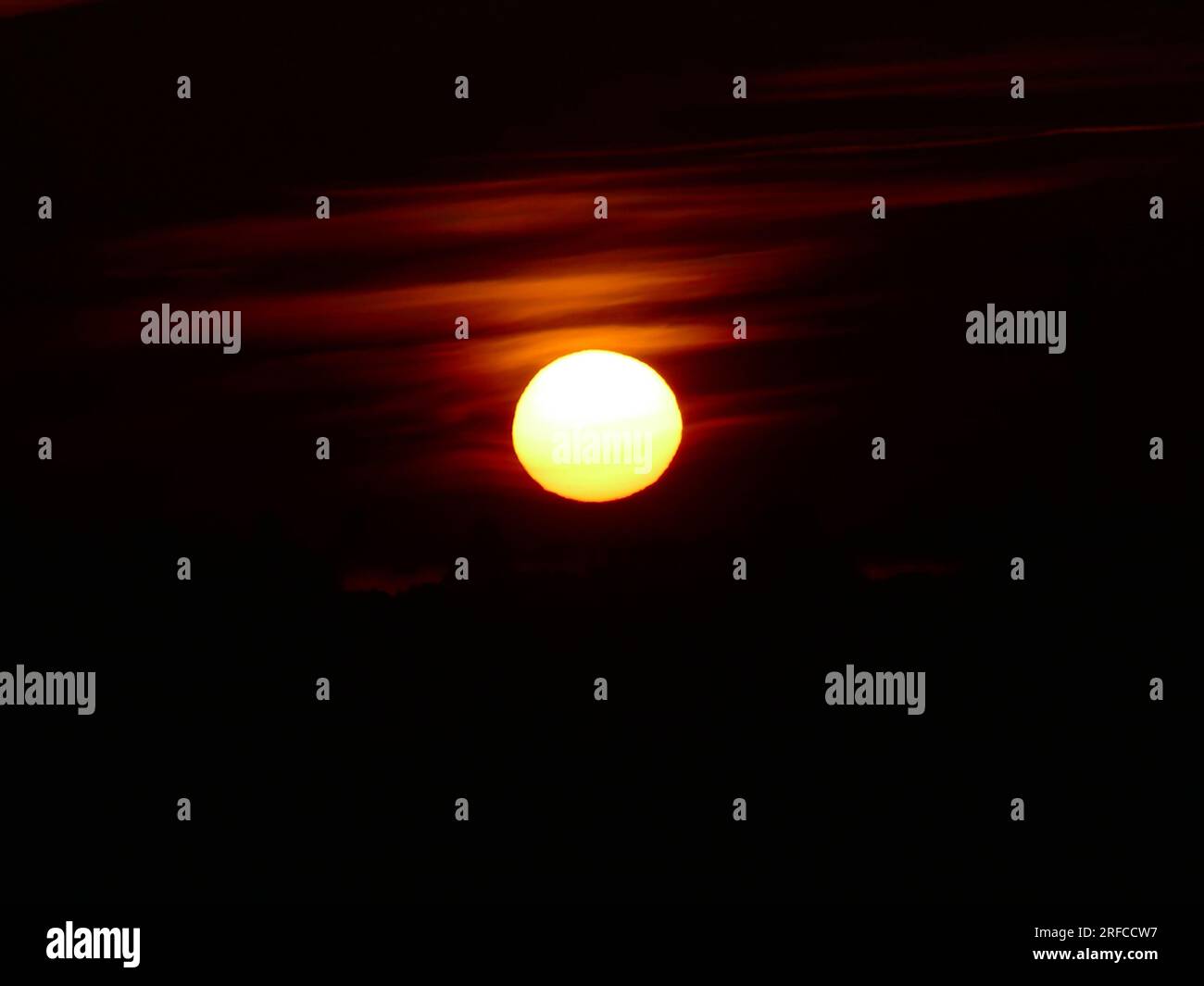 The disk of the northern rising sun on a sultry, damp midsummer day ...