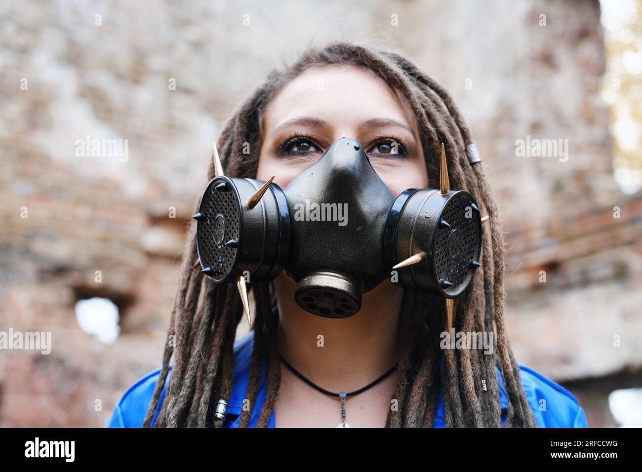 Woman wearing gas mask with spikes in blue jacket and black dress ...