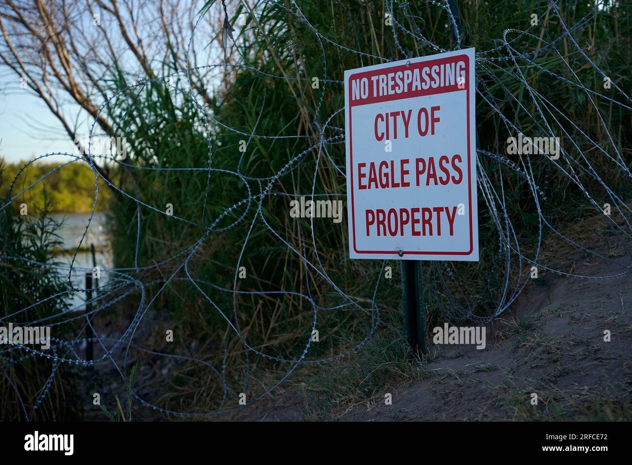 A 'no trespassing sign' and concertina wire are seen along the banks of ...