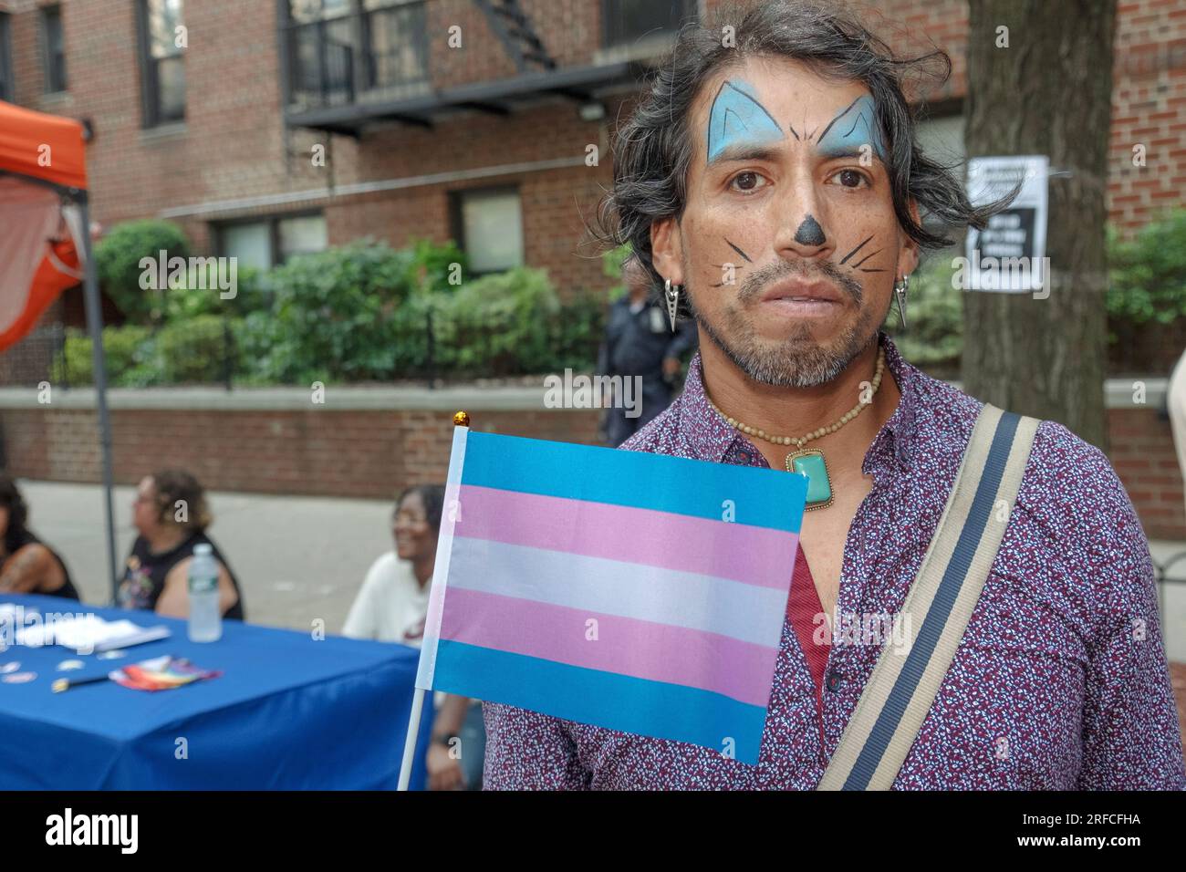 A trans person with cat markings holds a trans flag at Transfest 2023 ...