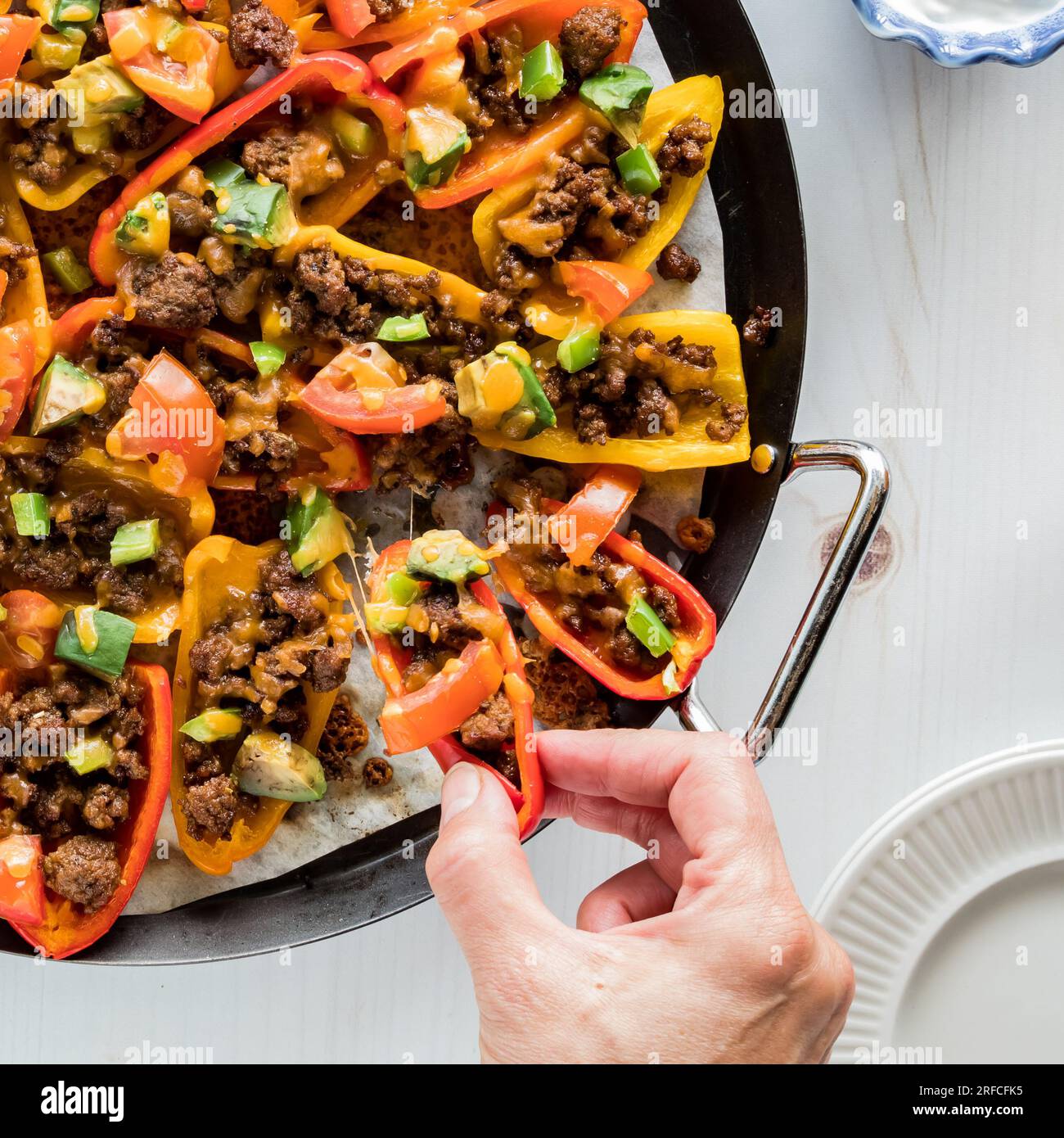 Mini bell pepper nachos with a hand taking one from the platter Stock ...