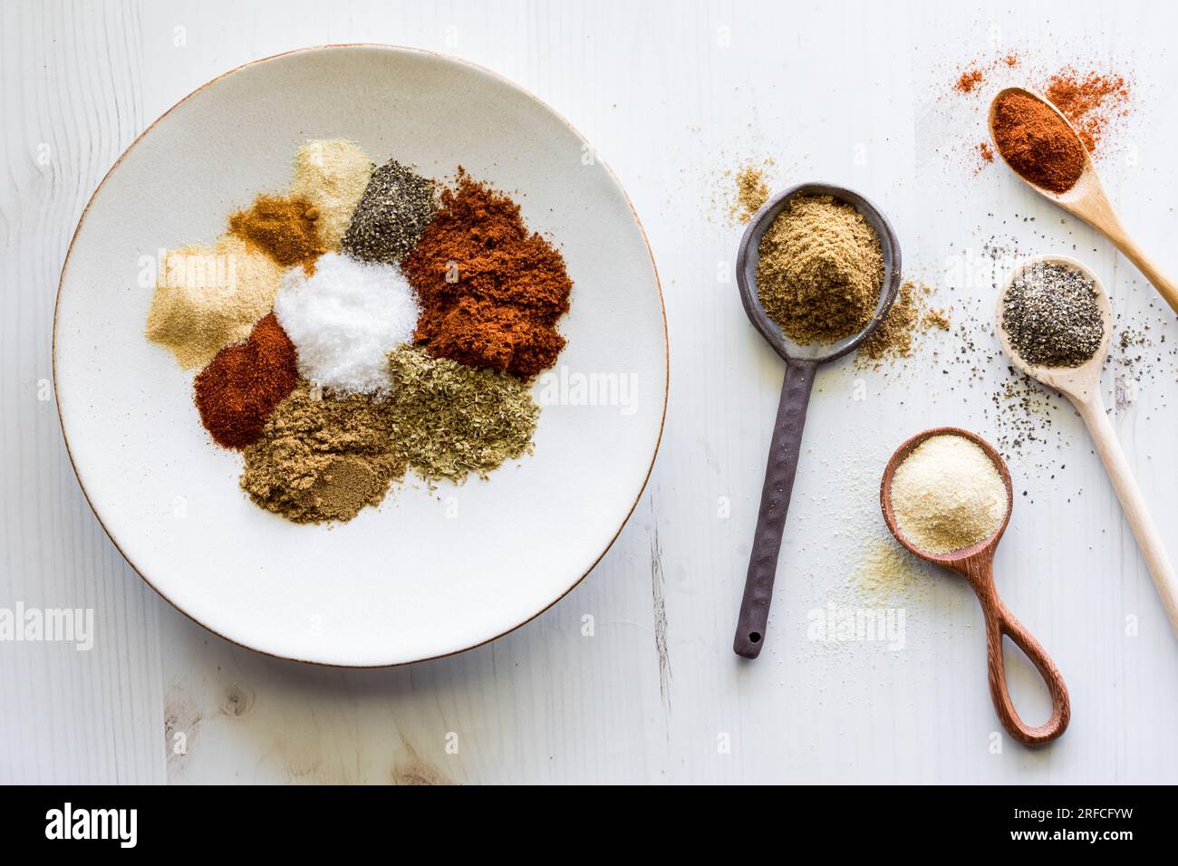 Various spoons with messy piles of spices used to make a taco seasoning ...