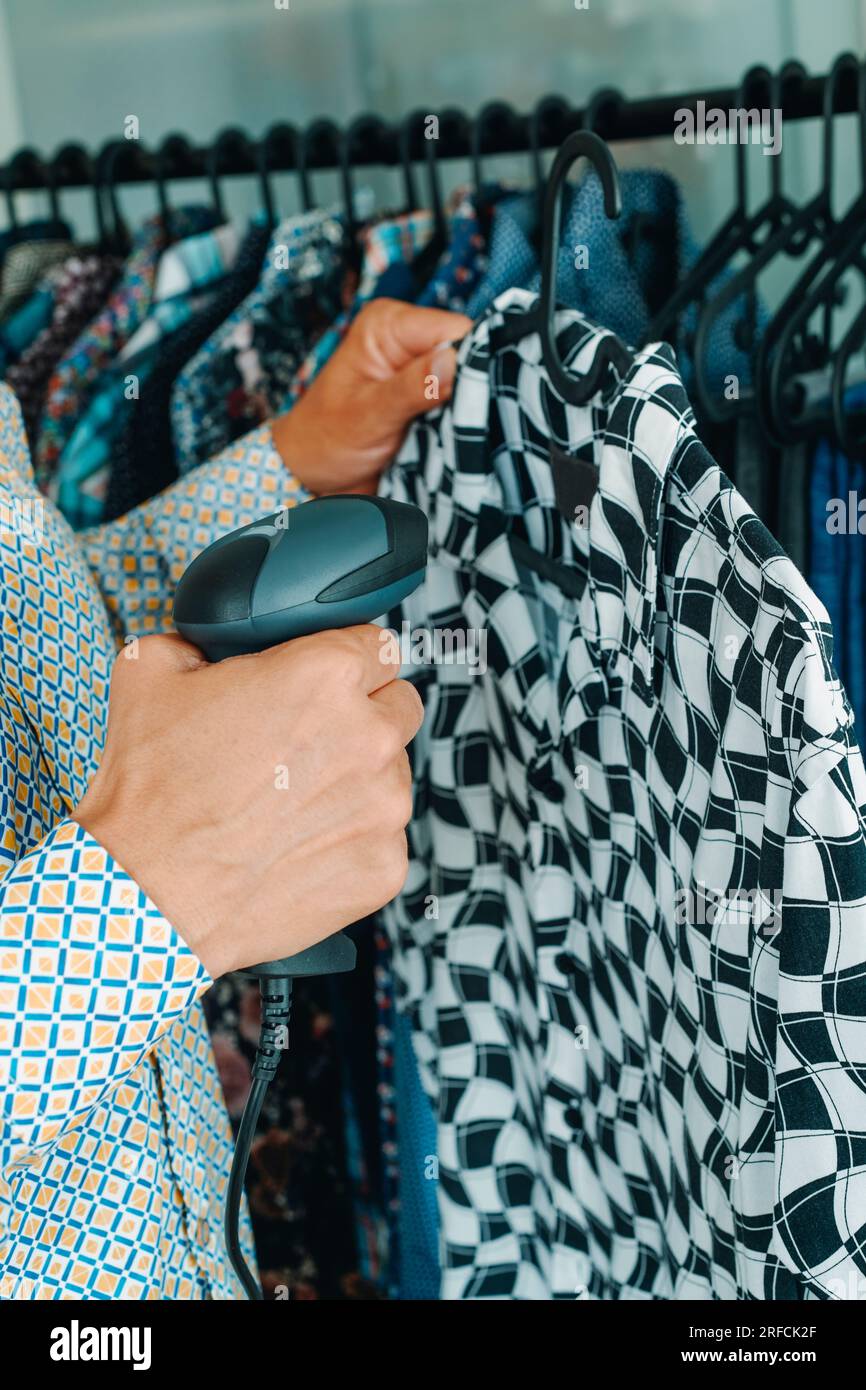 a shop assistant in a clothes shop is using a barcode scanner to scan ...