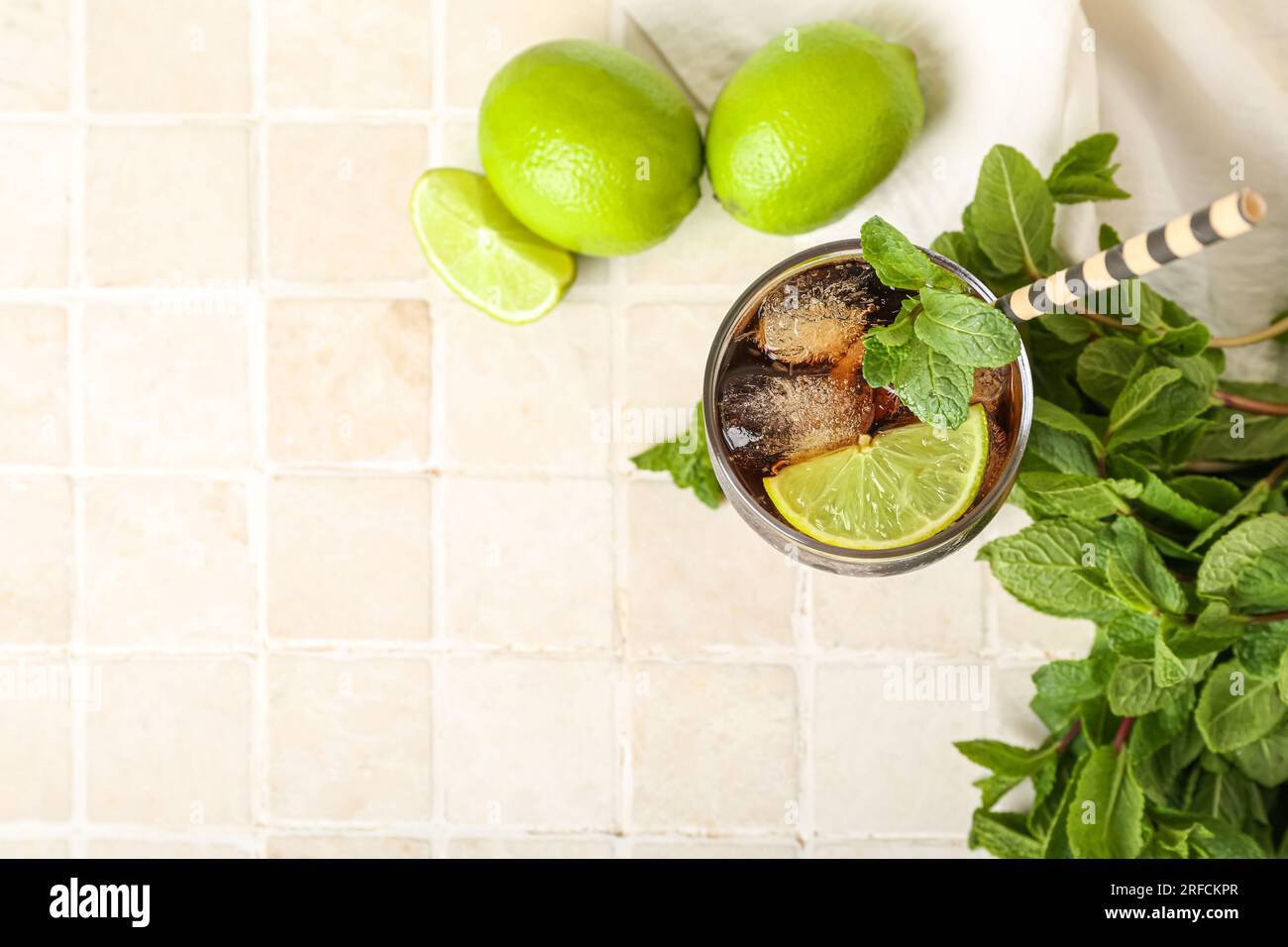 Glass of tasty Cuba Libre cocktail on light tile background Stock Photo ...