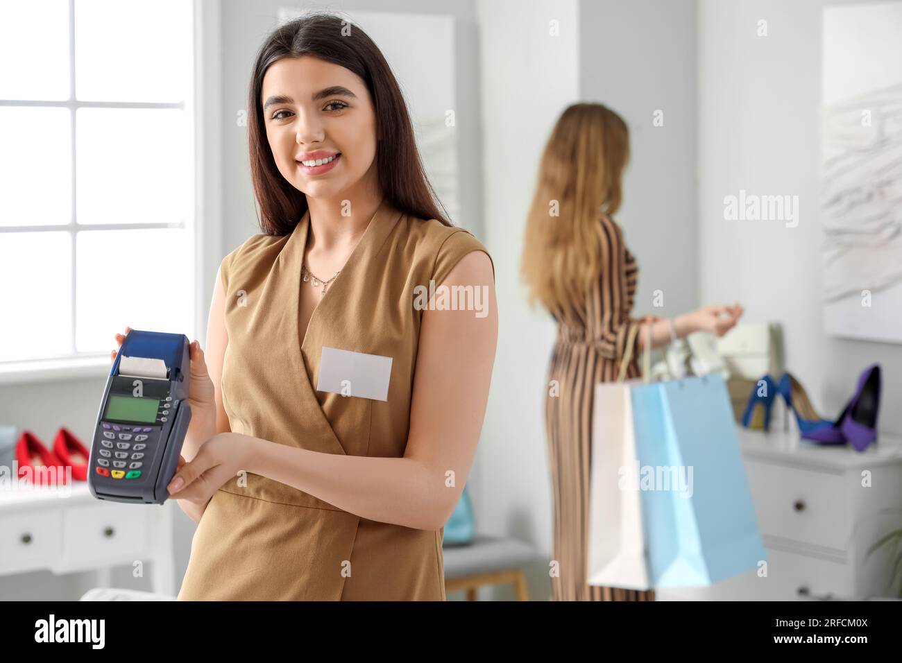 Female sales assistant with payment terminal in shoe shop Stock Photo ...