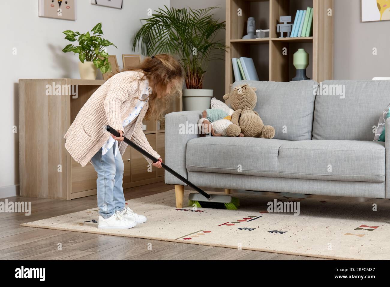 Cute little girl sweeping carpet with broom at home Stock Photo - Alamy