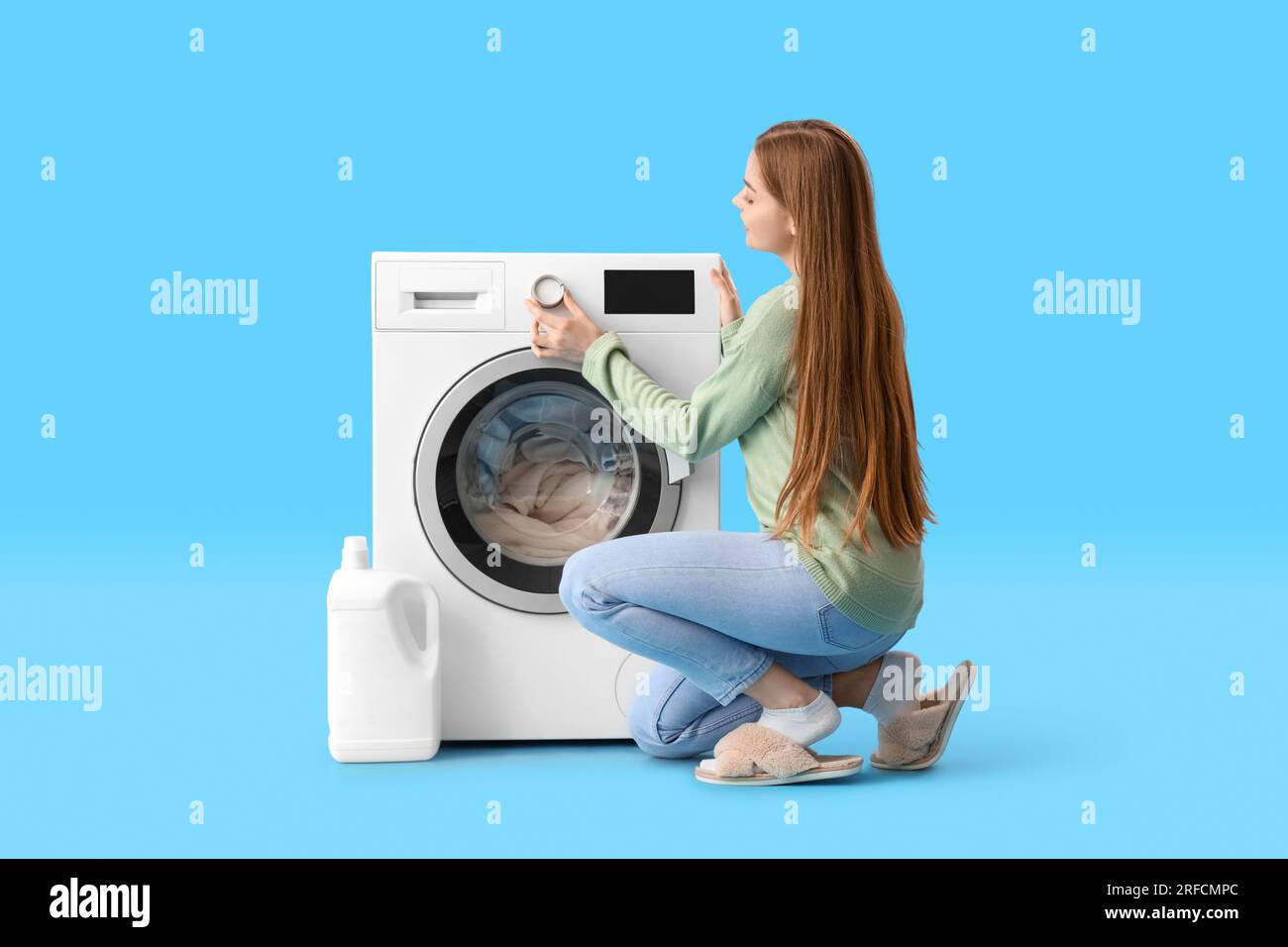 Pretty young woman setting up washing machine on blue background Stock ...