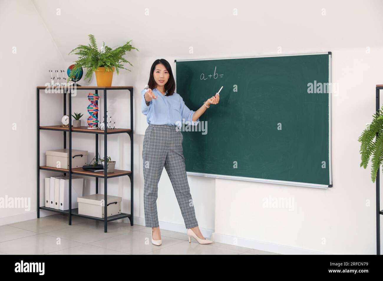 Female Asian teacher conducting Math near chalkboard in classroom Stock ...