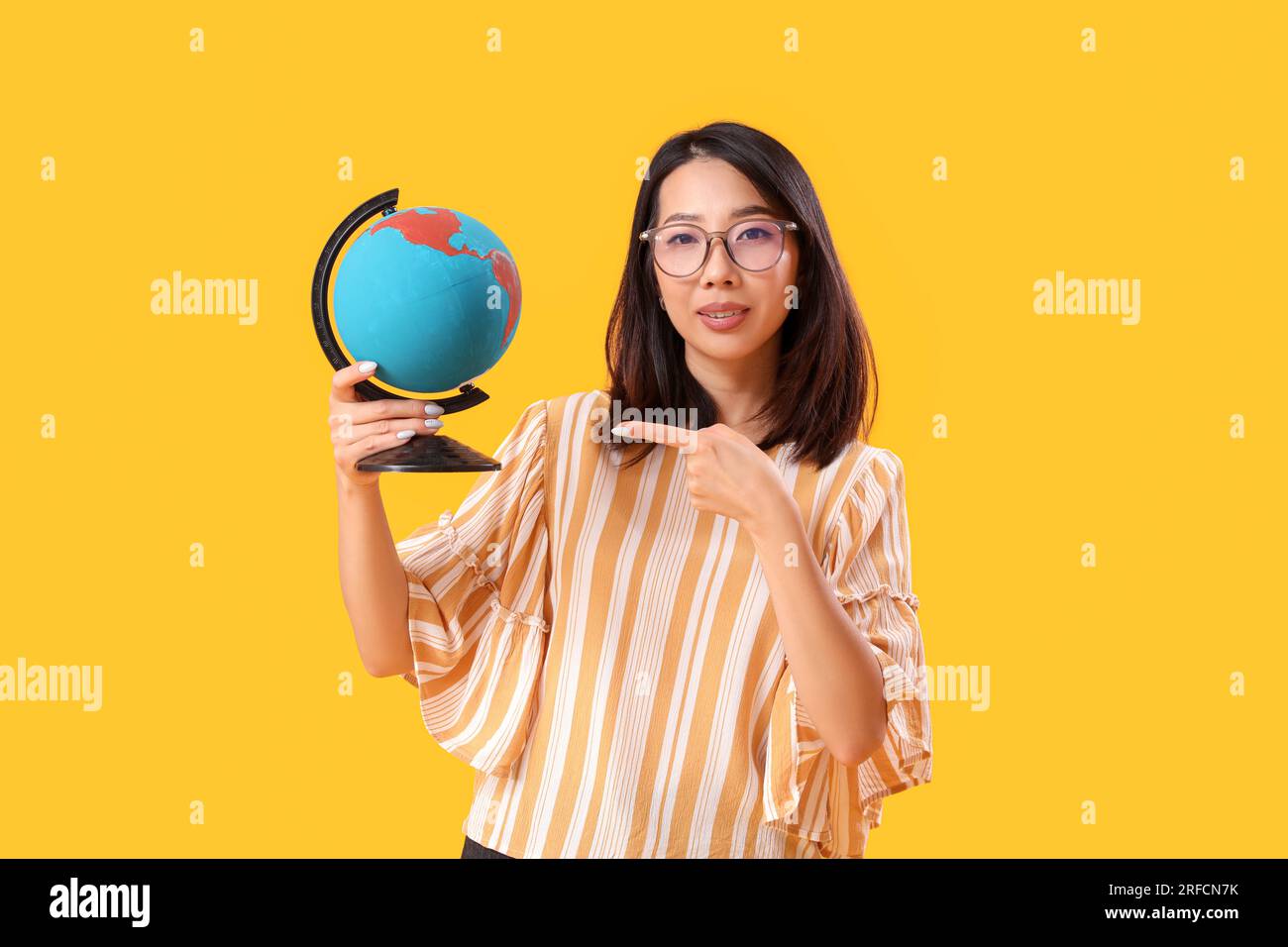 Female Asian Geography teacher with globe on yellow background Stock ...