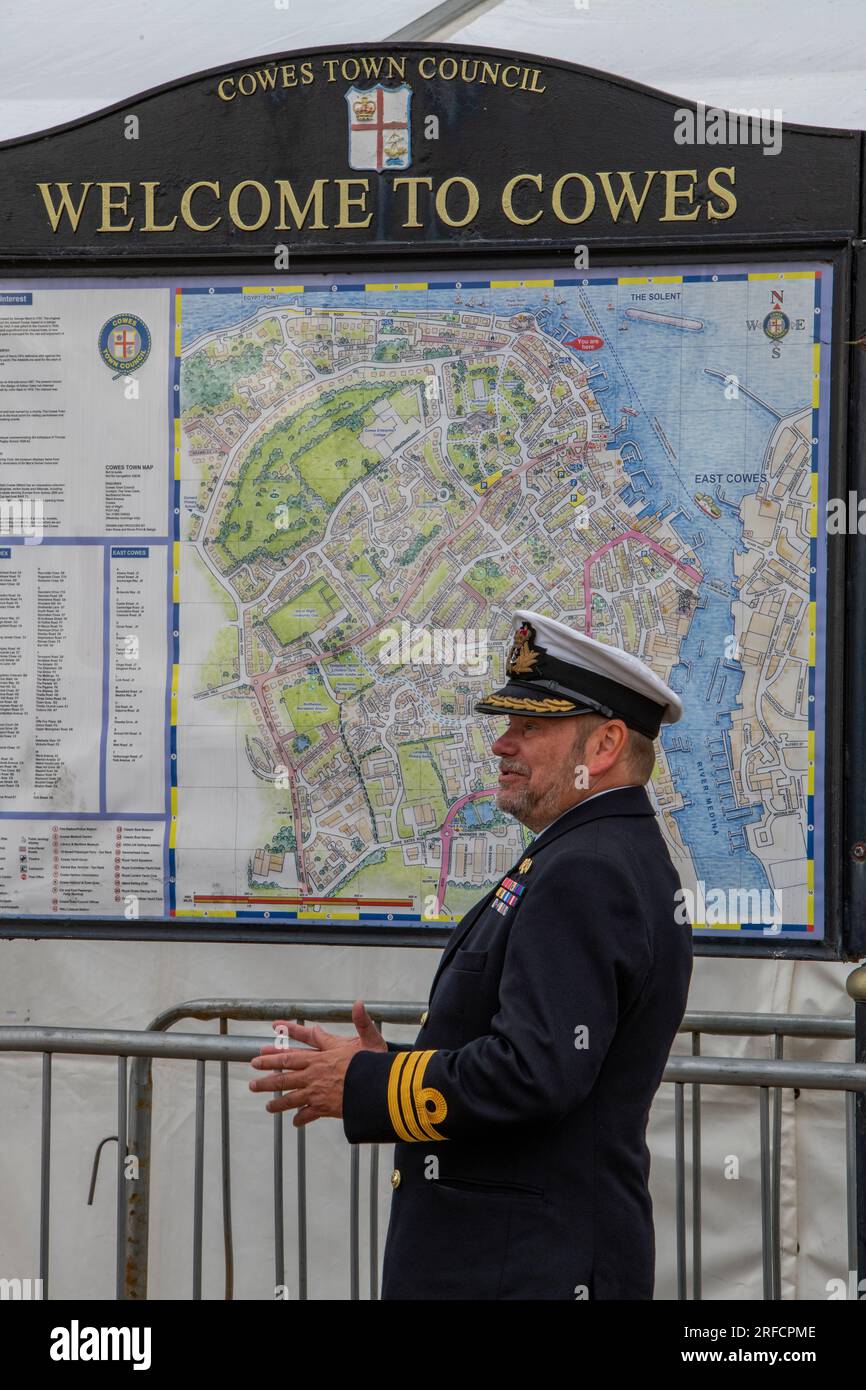 royal naval officer standing next to the welcome to cowes map board ...