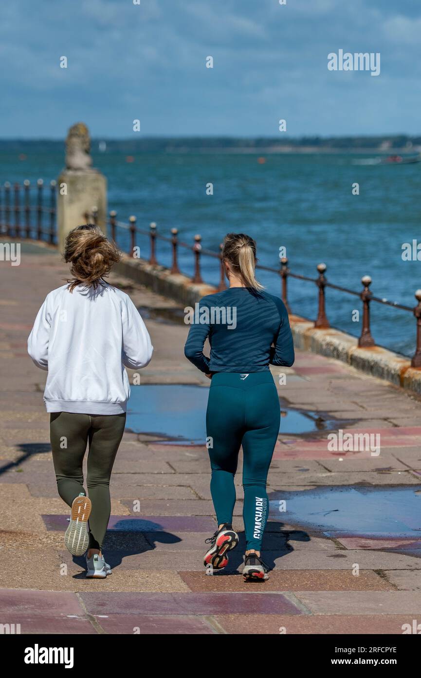 two females running along the seafront. two young women jogging at the ...