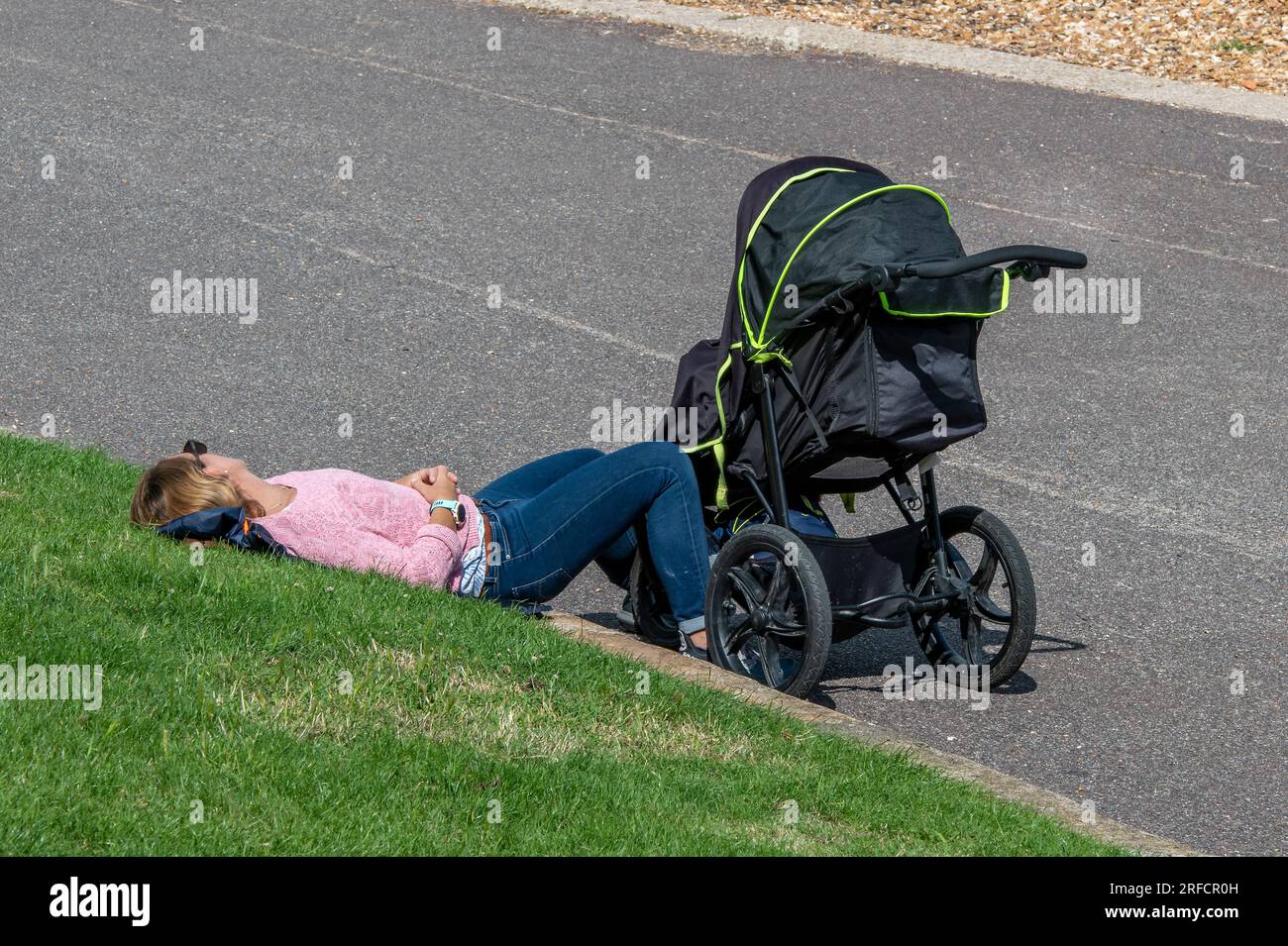 young mother with pushchair taking a rest. young mum sleeping next to ...