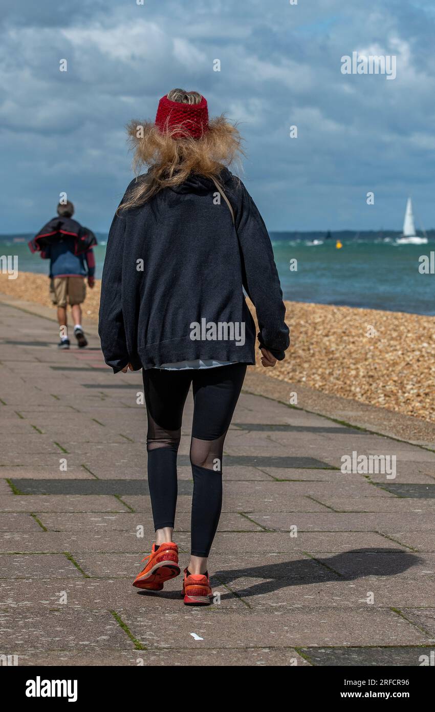 older lady power walking along a pathway at the seaside. lady wearing ...