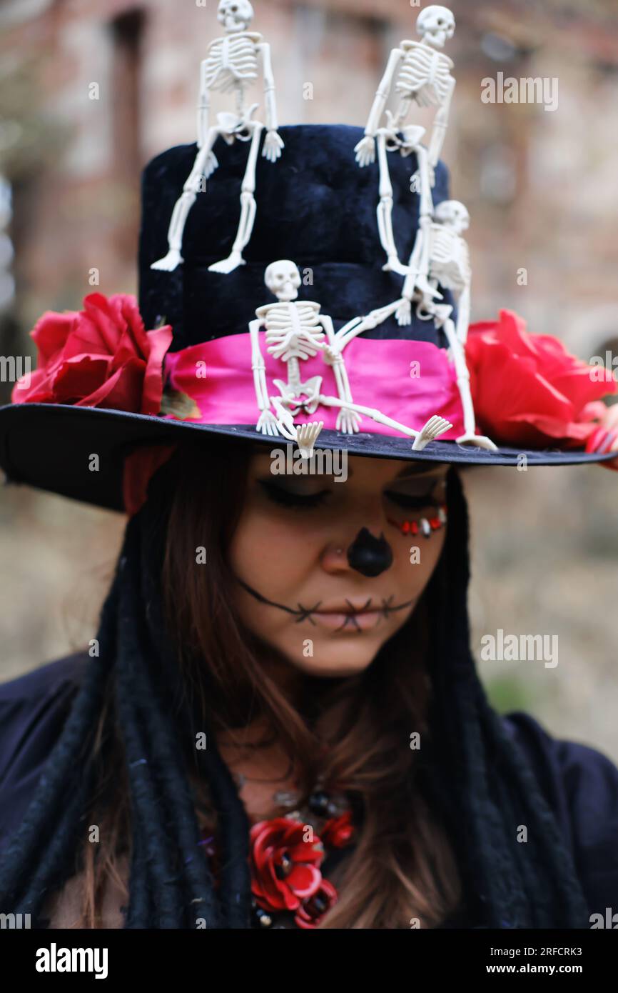 A woman in the image of Baron Saturday poses against the backdrop of an old ruined brick ...