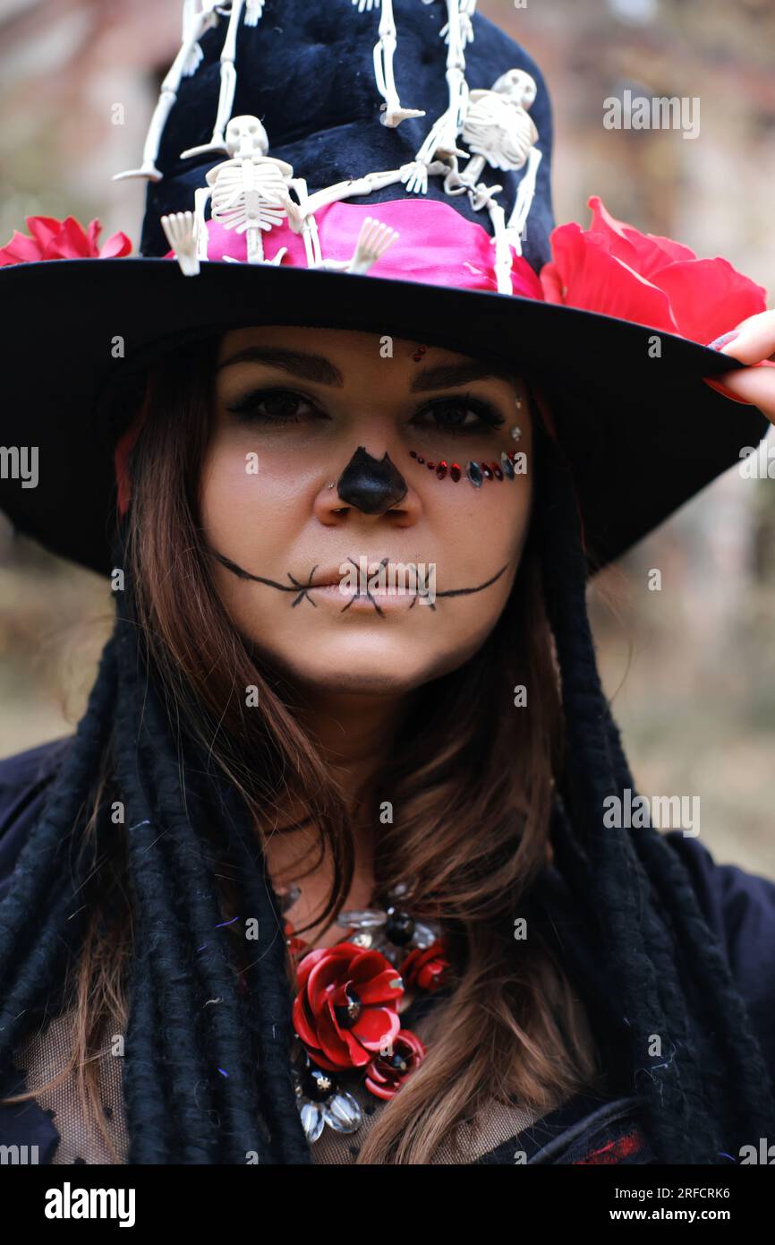 A woman in the image of Baron Saturday poses against the backdrop of an old ruined brick ...