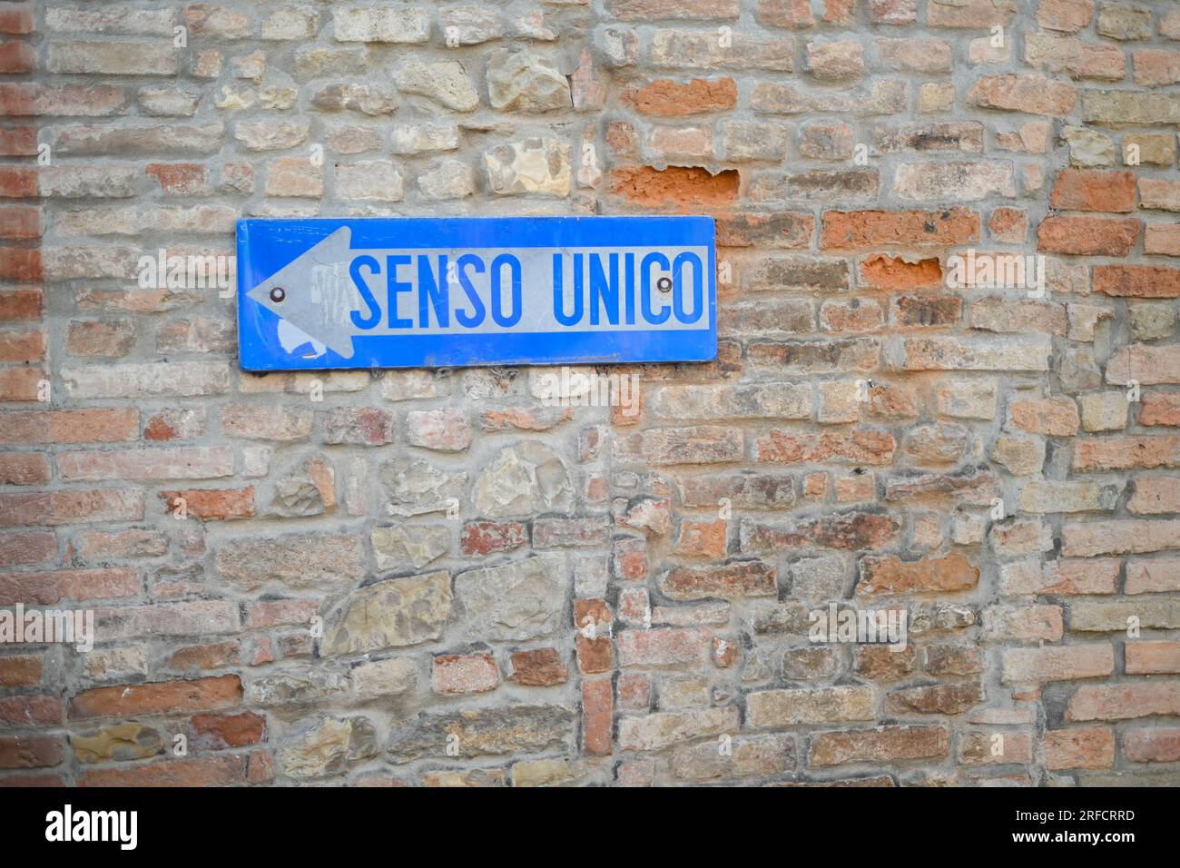 blue one way italian traffic street sign over an old brick wall senso ...