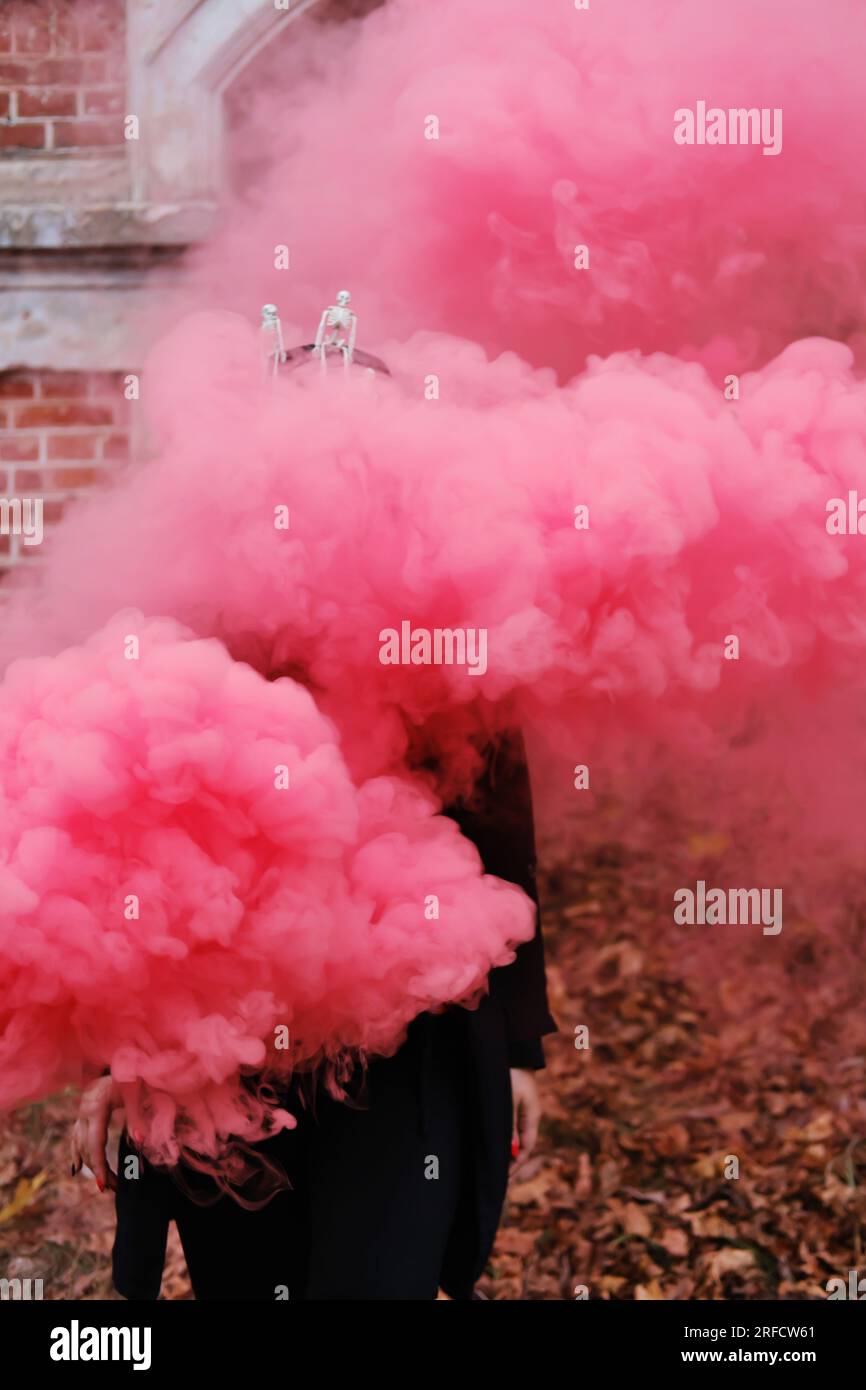 A woman in the guise of Baron Sabbath poses in red smoke. Smoke covers ...