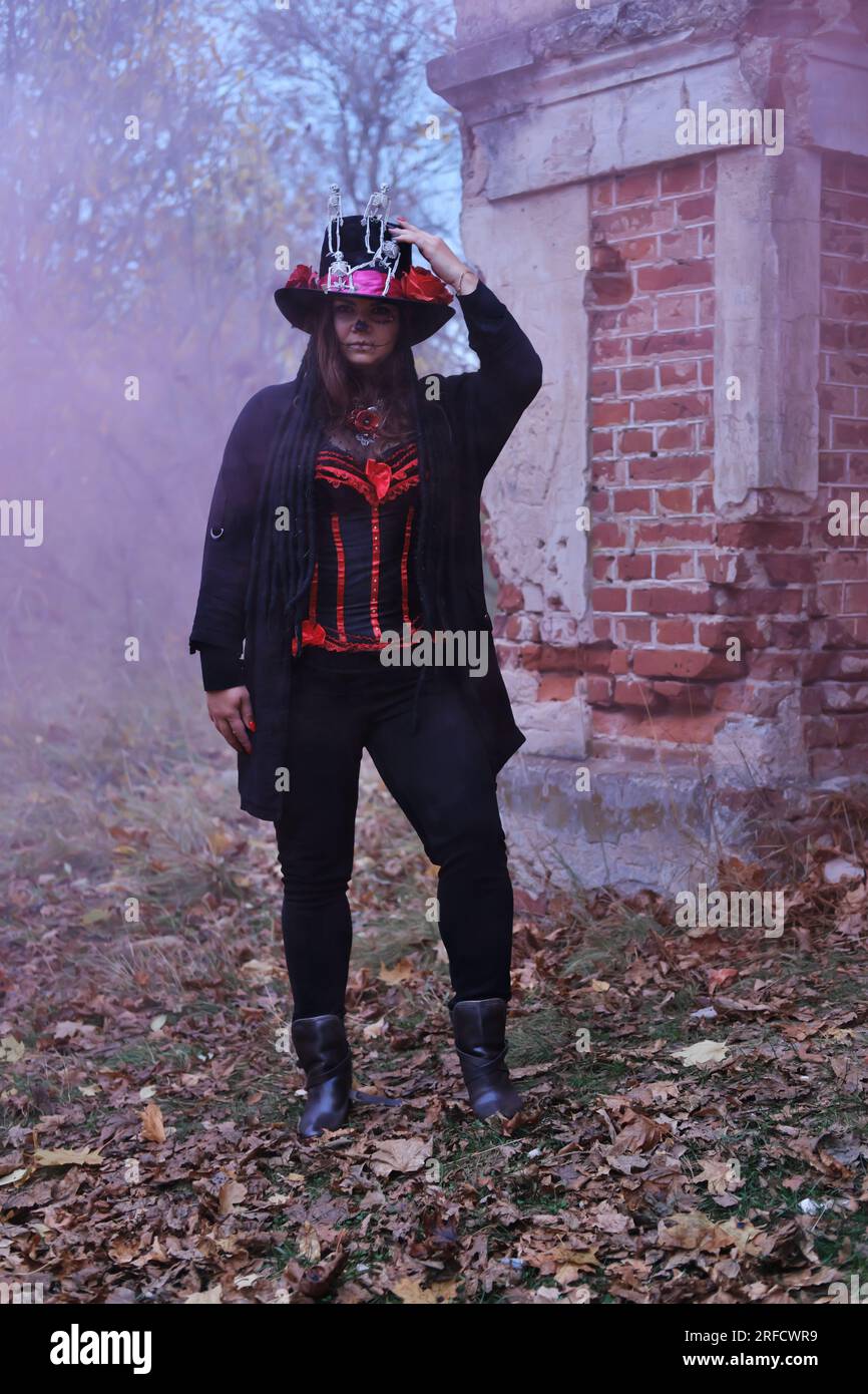 A woman in the guise of Baron Sabbath poses in red smoke. The model is ...