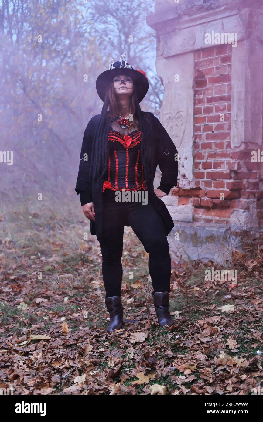 A woman in the guise of Baron Sabbath poses in red smoke. The model is ...