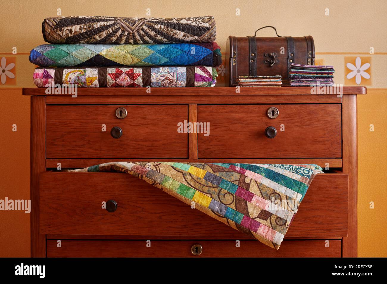 Stack of traditional quilts and wooden chest on chest of drawers Stock ...
