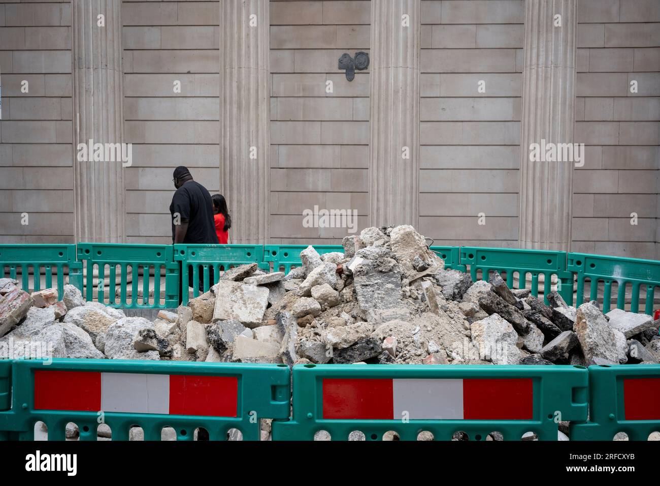 A heap of concrete rubble is piled up beneath the tall pillars and ...