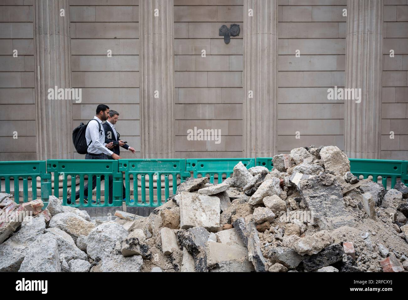 A heap of concrete rubble is piled up beneath the tall pillars and ...