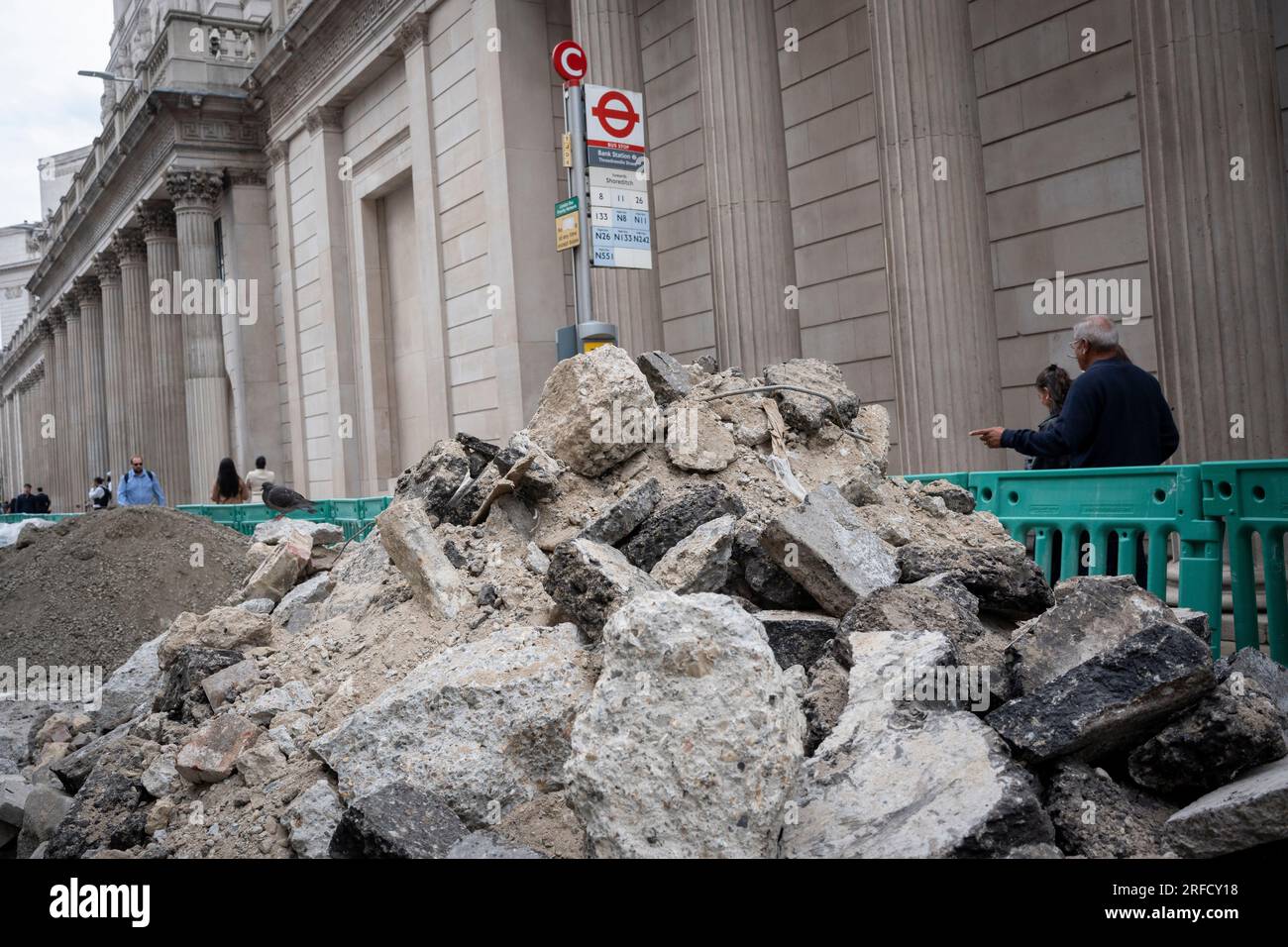 A heap of concrete rubble is piled up beneath the tall pillars and ...