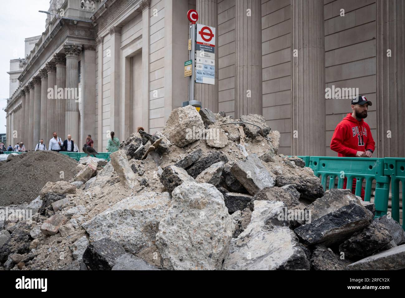 A heap of concrete rubble is piled up beneath the tall pillars and ...