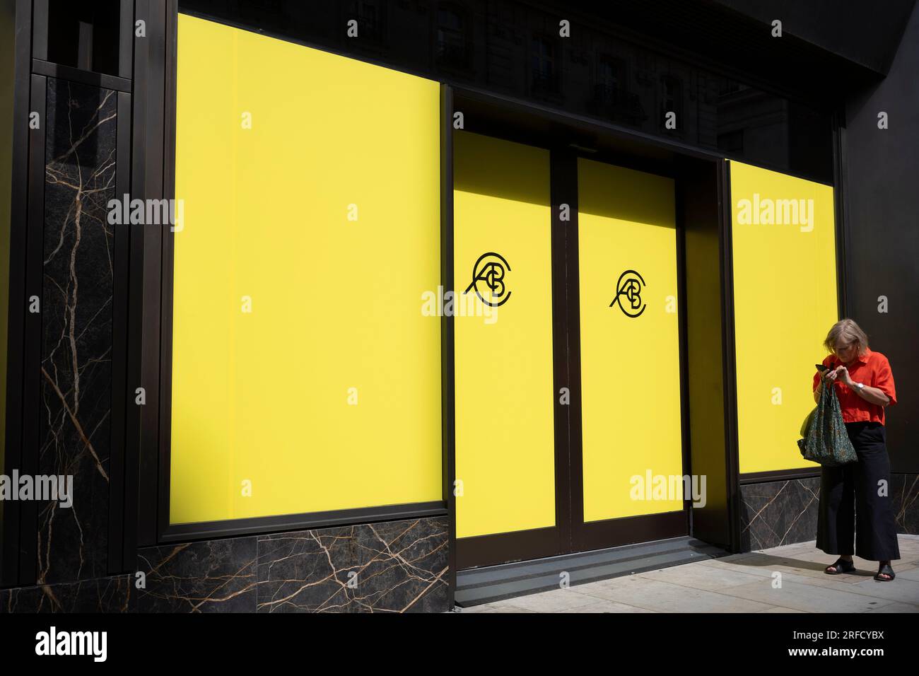 A person walks past the yellow hoarding for a forthcoming showroom for ...