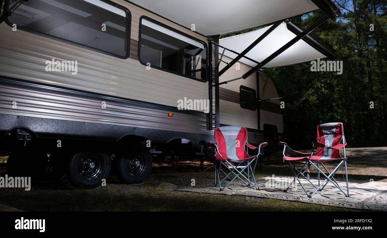 Camping trailer set up in a forested campground with awnings out and ...