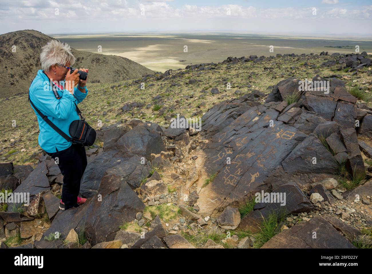 A tourist is photographing the Khavtsgait Petroglyphs dating from ...