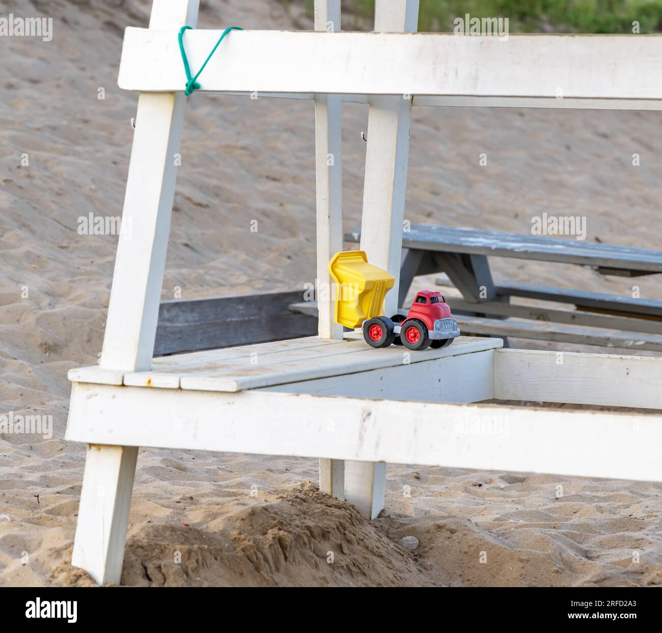 Small red and yellow plastic dump truck sitting on a life guard stand ...
