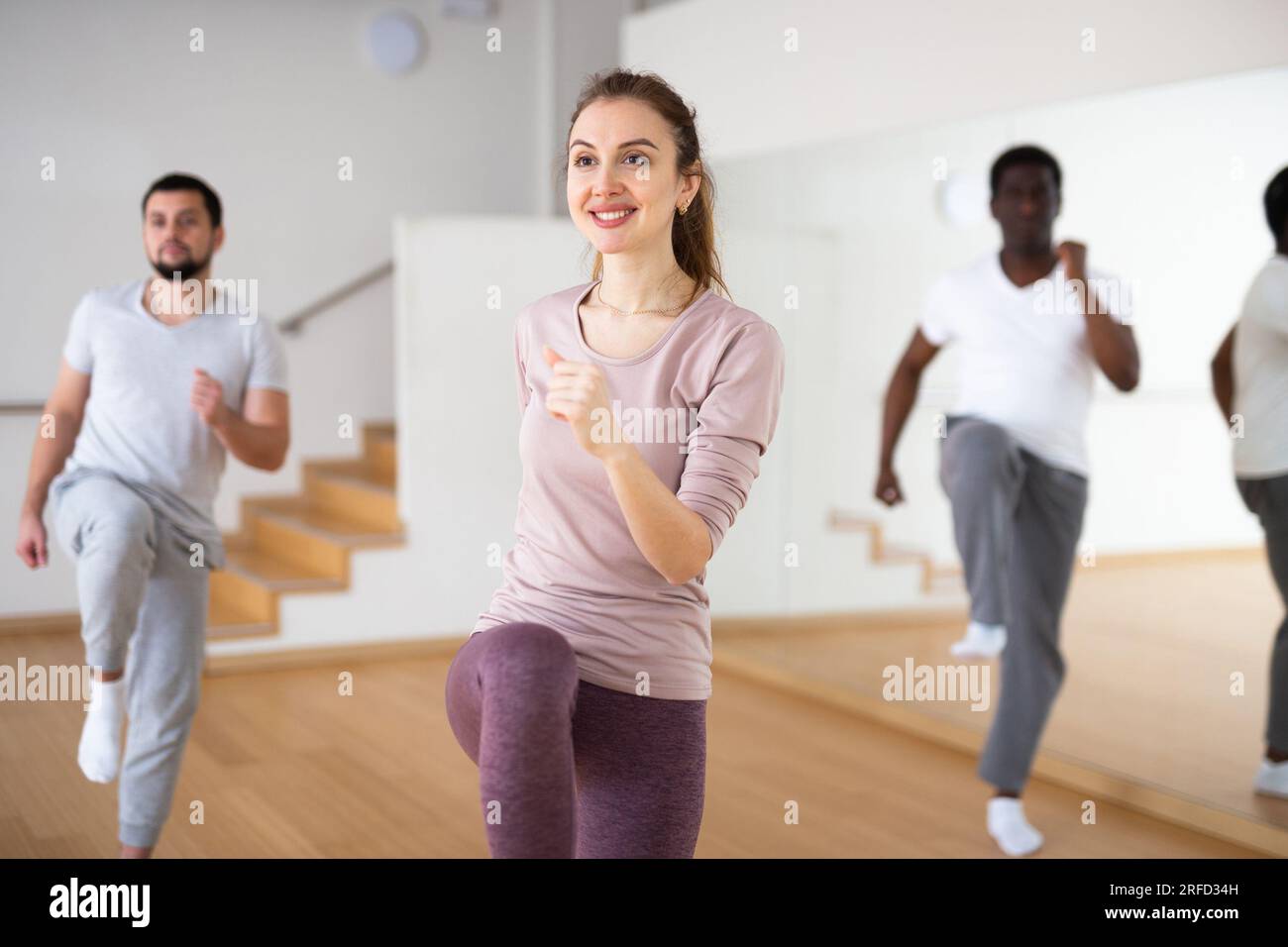Woman dancing aerobic dance with men in studio Stock Photo - Alamy