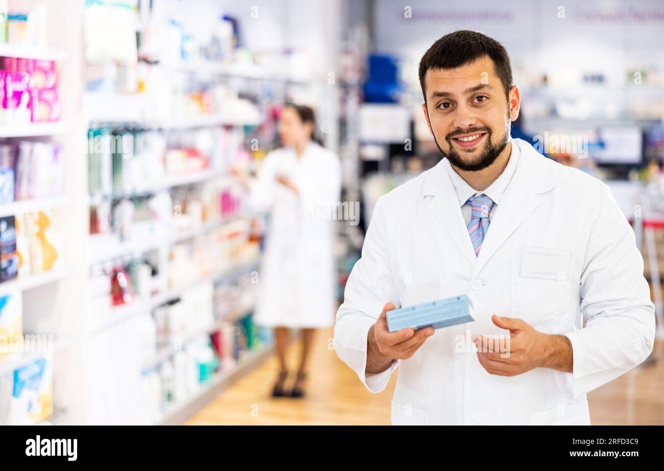 Male pharmacist offering product, working in drugstore Stock Photo - Alamy