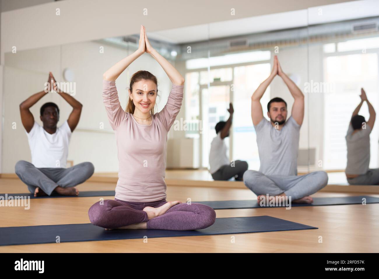 Woman sitting in Padmasana yoga position with arms in namaste above ...