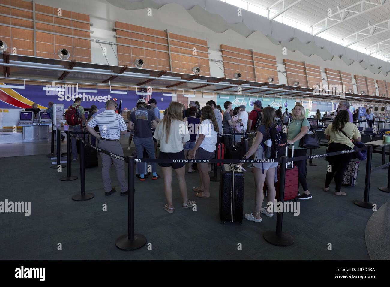 Passengers wait in line at a Southwest Airlines baggage ticket counter ...