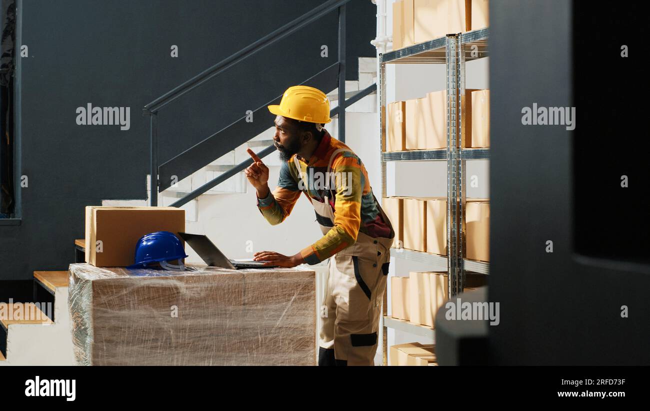 Storehouse workers taking boxes from racks, working with ladder and ...