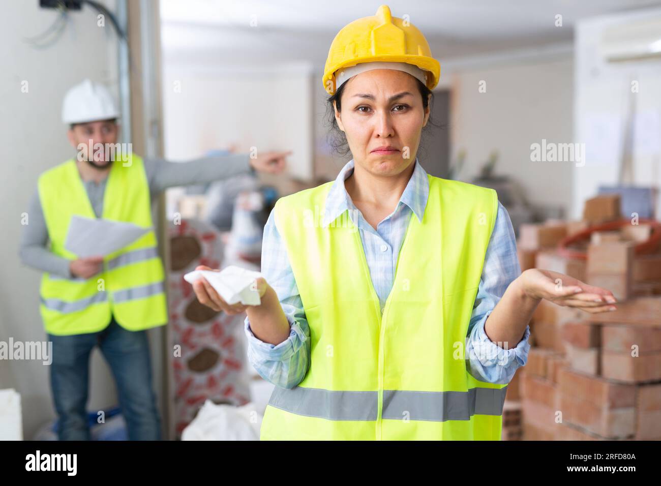 Puzzled female construction worker with displeased screaming foreman ...