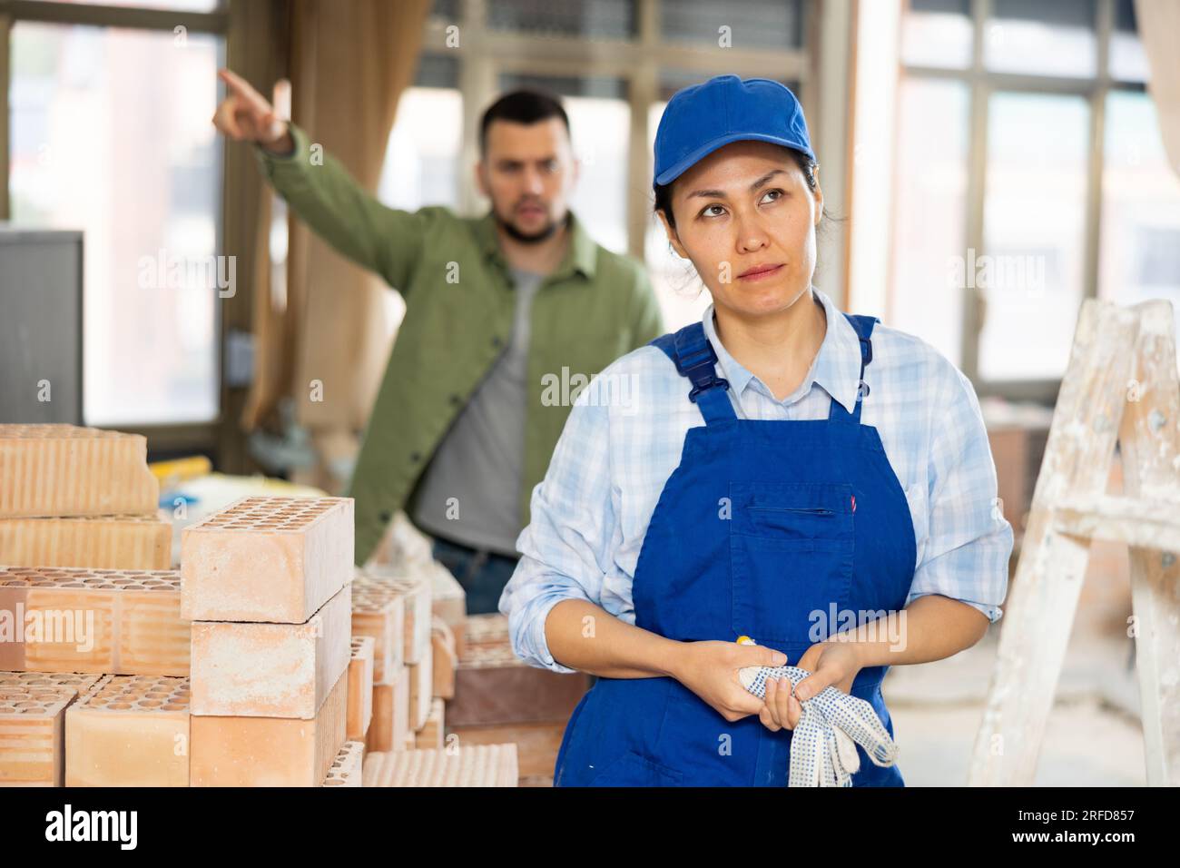 Upset female builder in building under construction with angry client ...