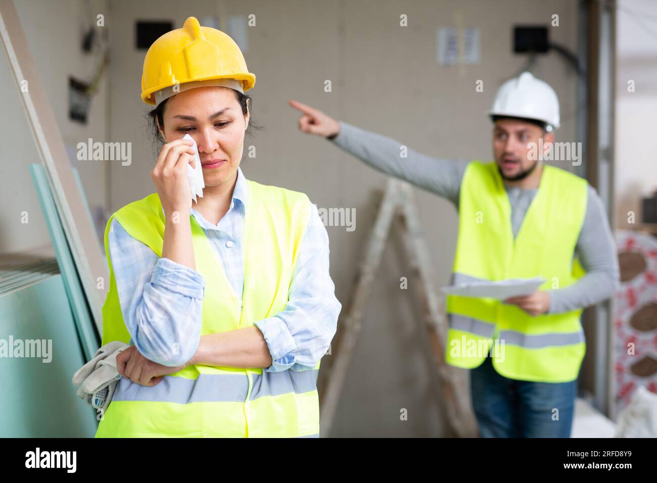 Crying female builder at construction site with displeased foreman ...