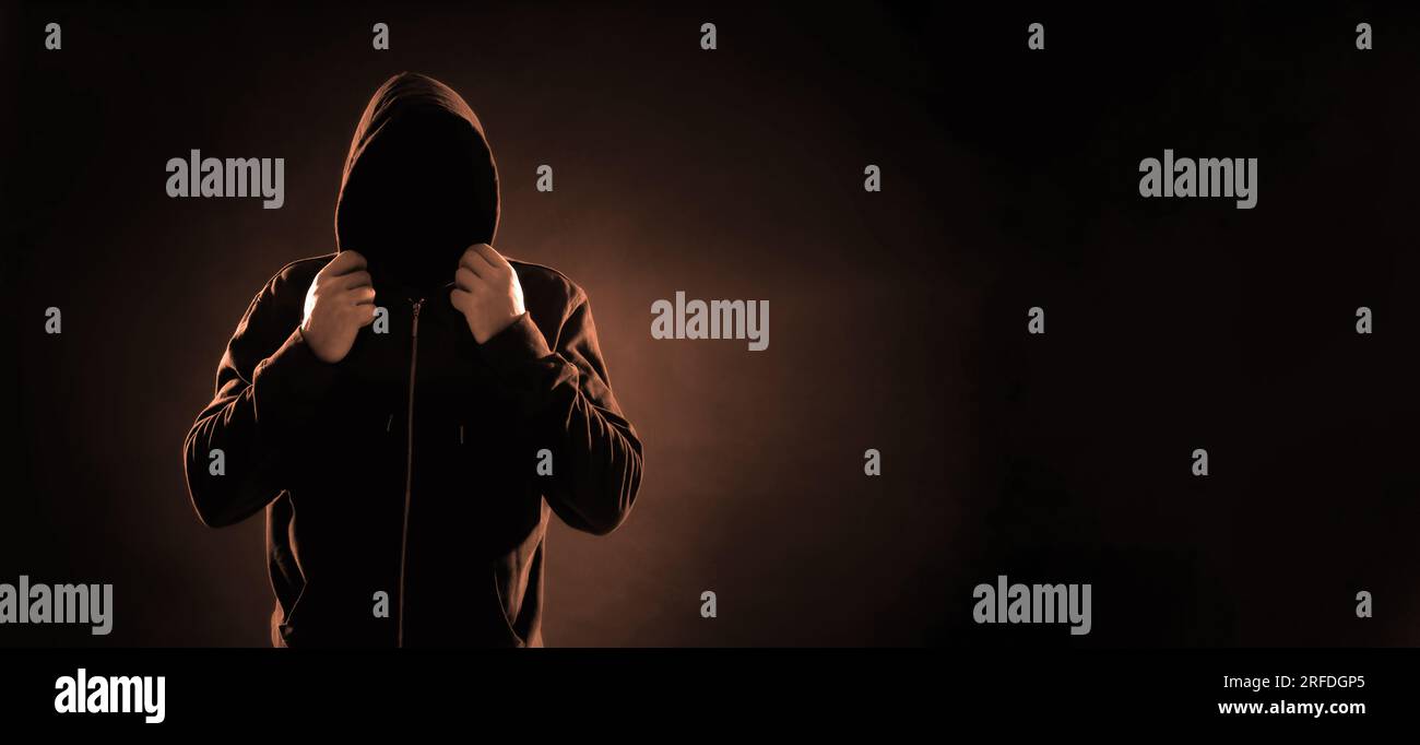 Anonymous man in hood on black background, space for text. Banner ...