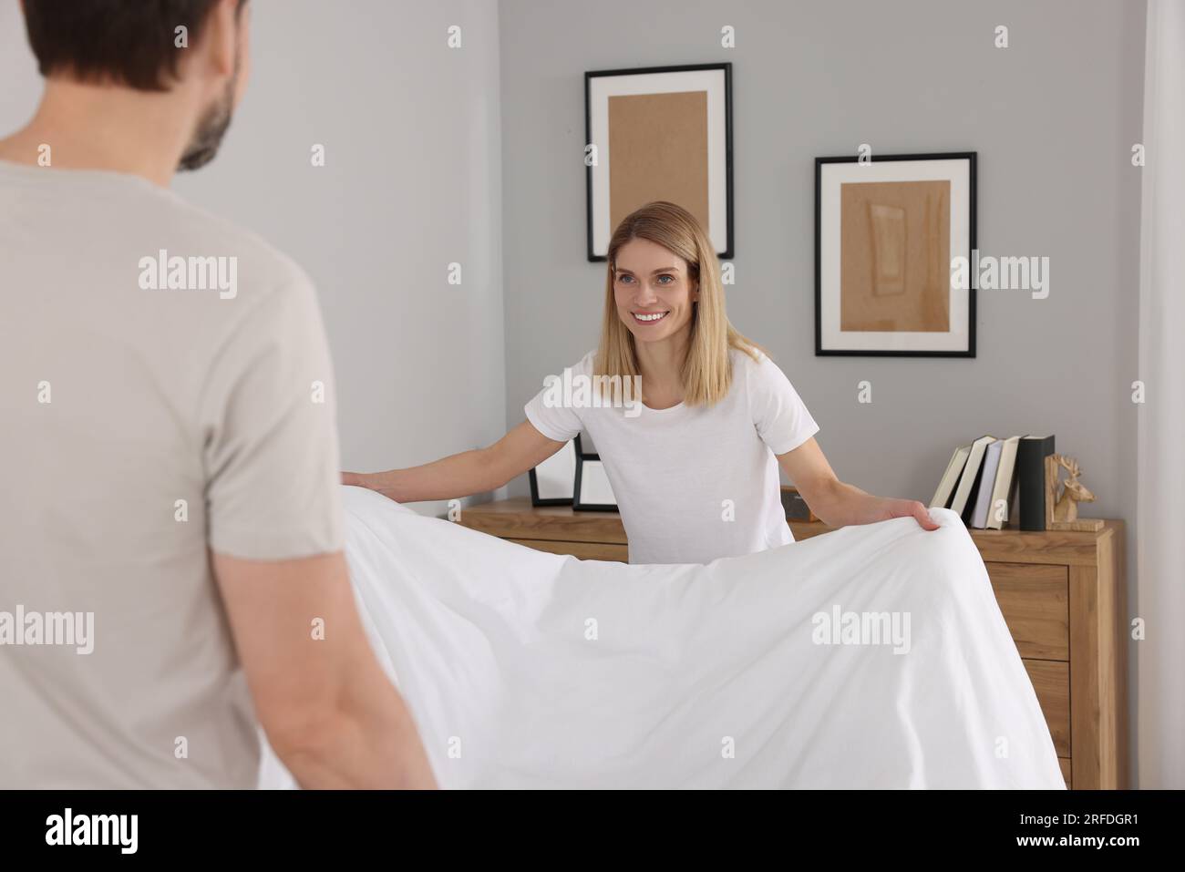 Couple changing bed linens in room. Domestic chores Stock Photo - Alamy