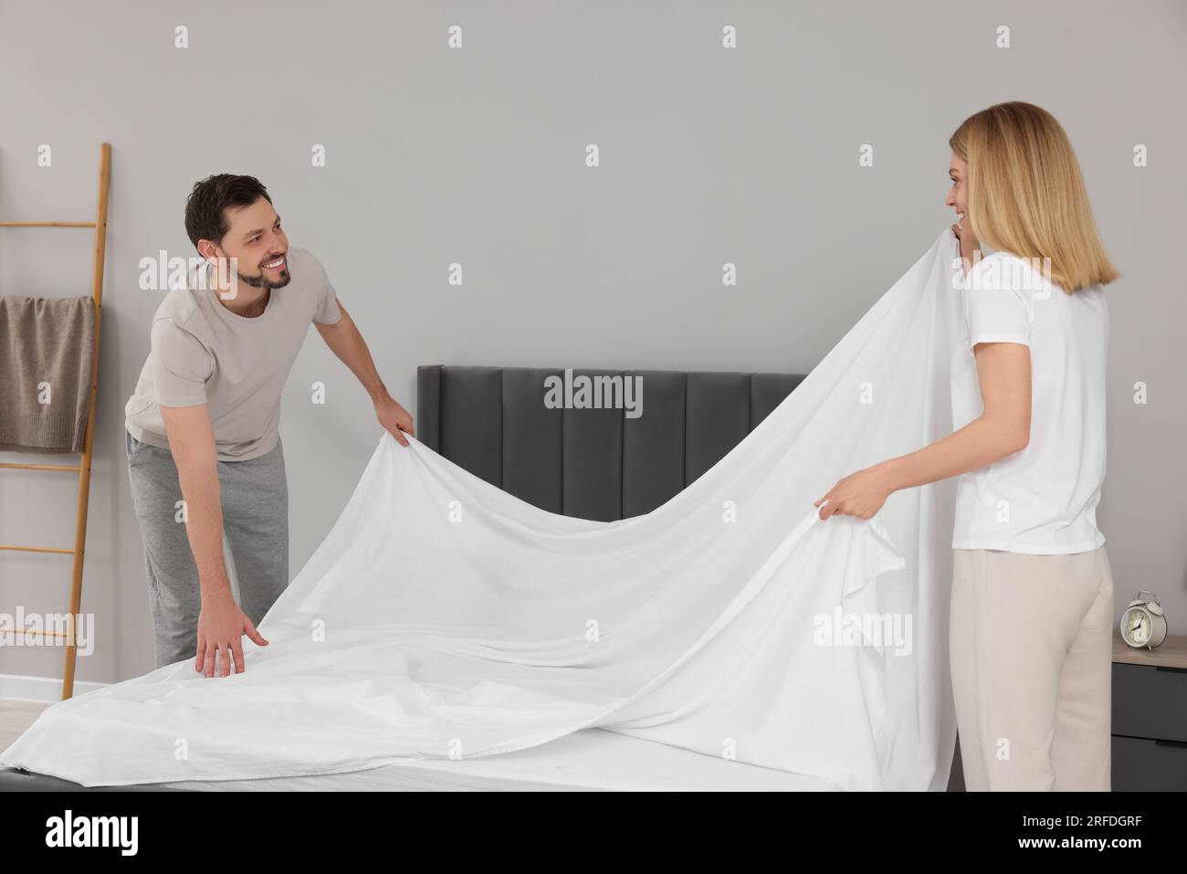 Couple changing bed linens in room. Domestic chores Stock Photo - Alamy