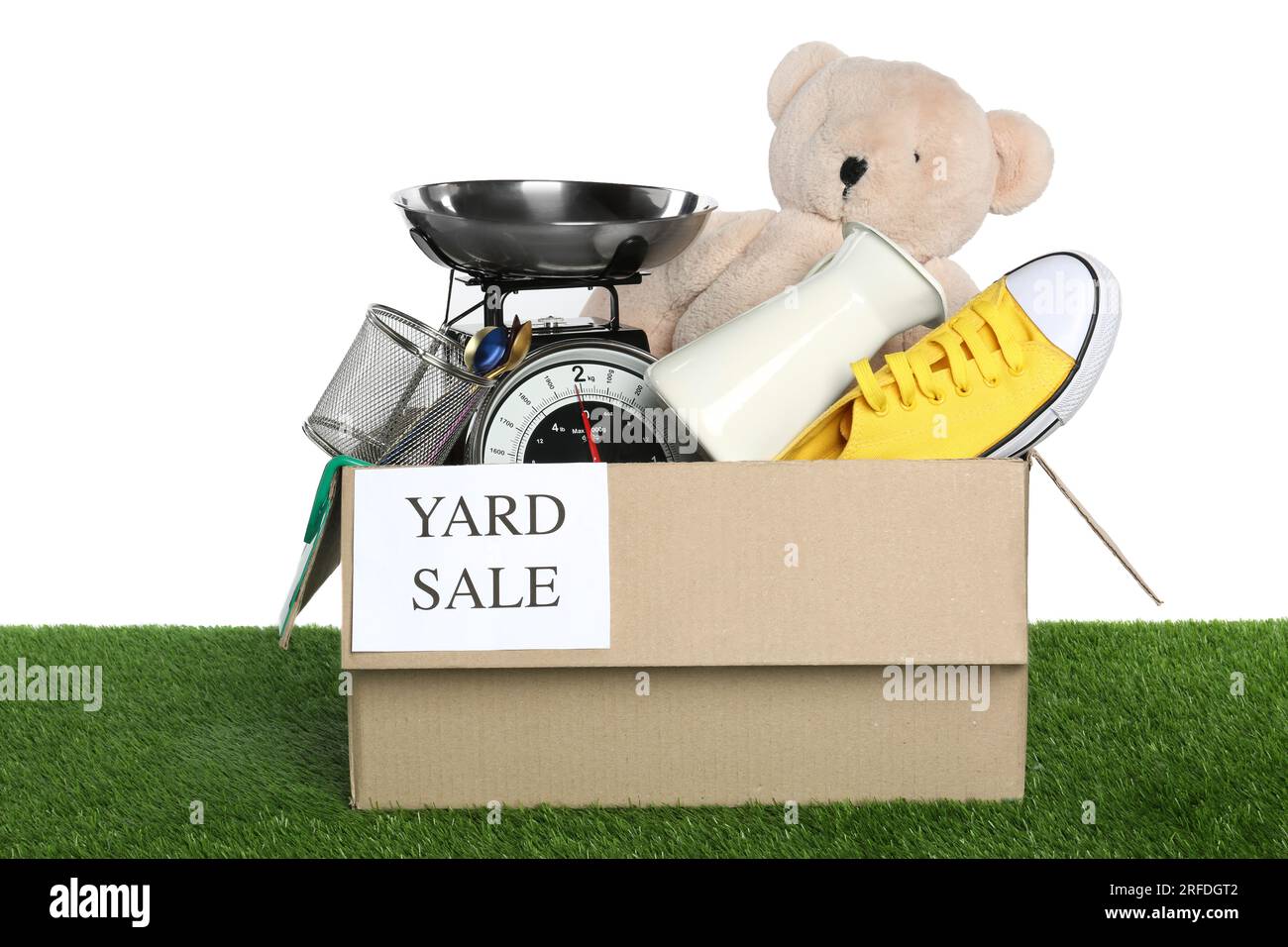 Sign Yard Sale written on box with different stuff on green grass ...