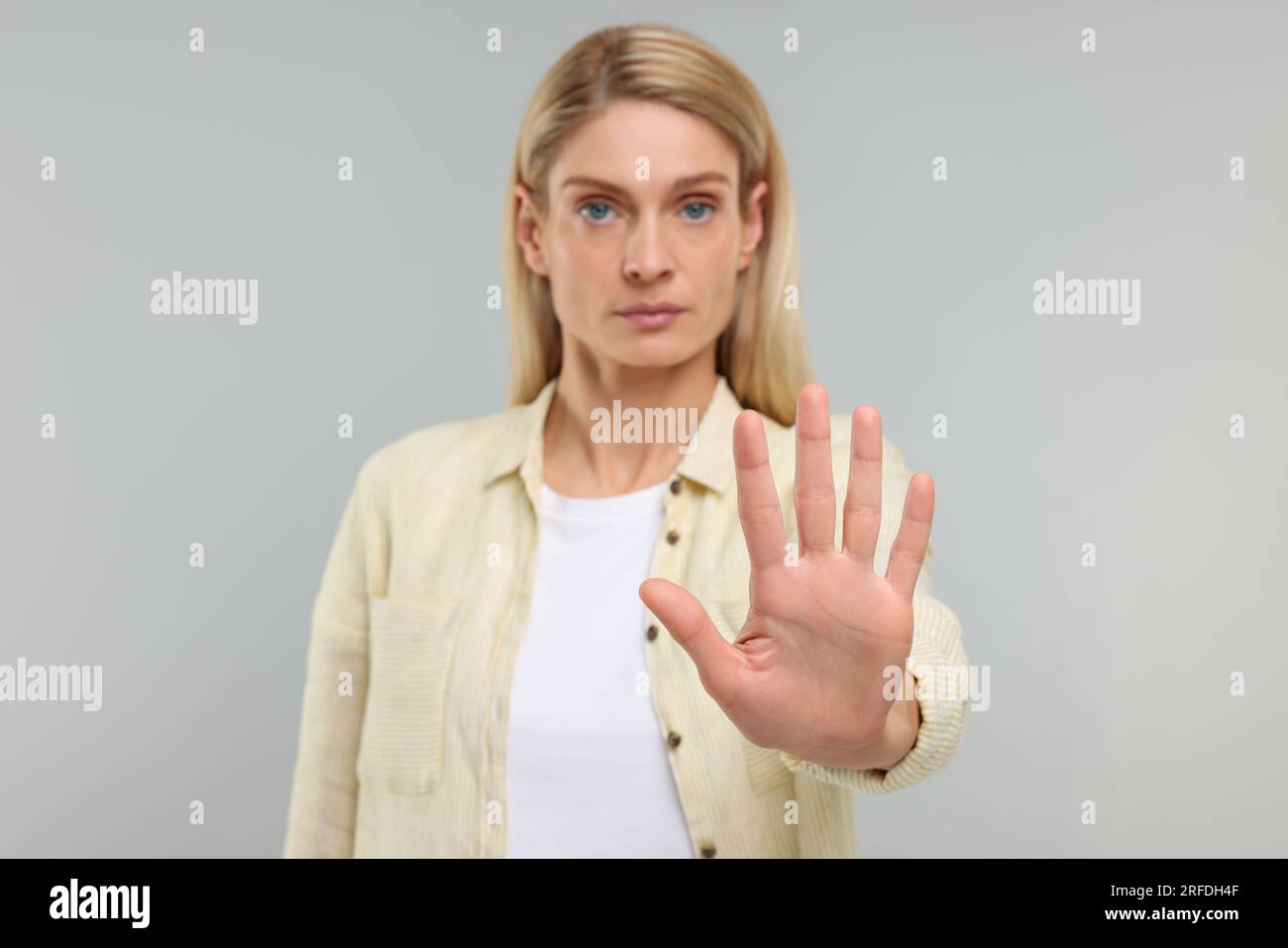 Woman showing stop gesture on grey background Stock Photo - Alamy