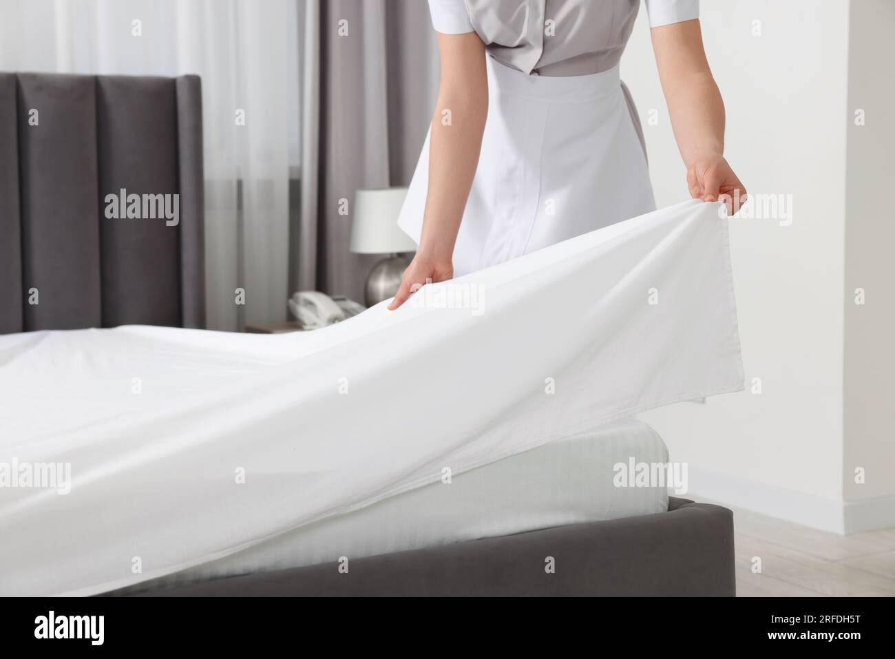 Maid making bed in hotel room, closeup Stock Photo - Alamy