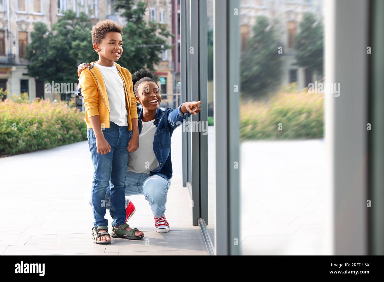 Happy mother pointing at window and her son outdoors Stock Photo - Alamy