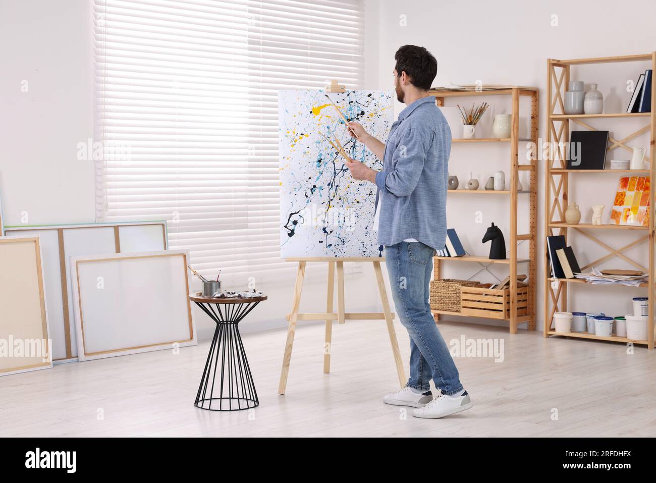Man painting in studio, back view. Using easel to hold canvas Stock ...